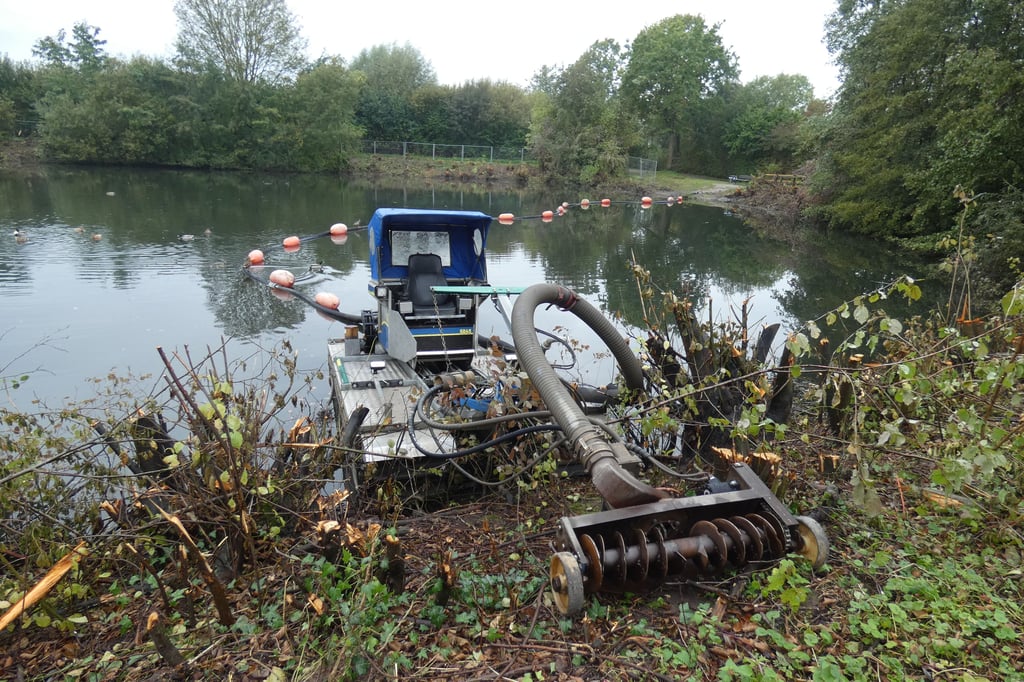 Schwimmender Bagger macht am Ufer fest